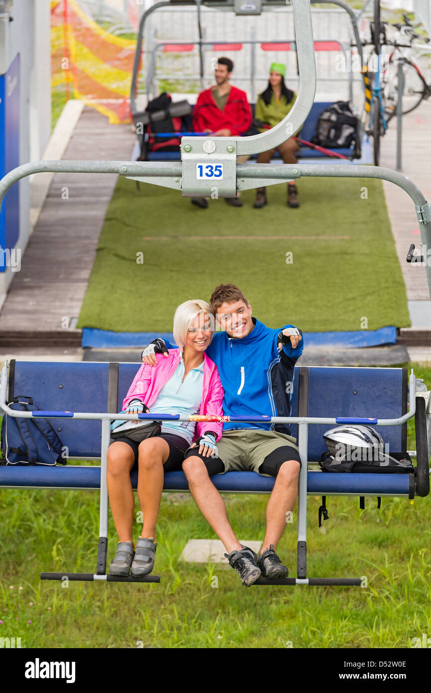 Cuddling couple pointing on chair lift in sweatsuits Stock Photo - Alamy