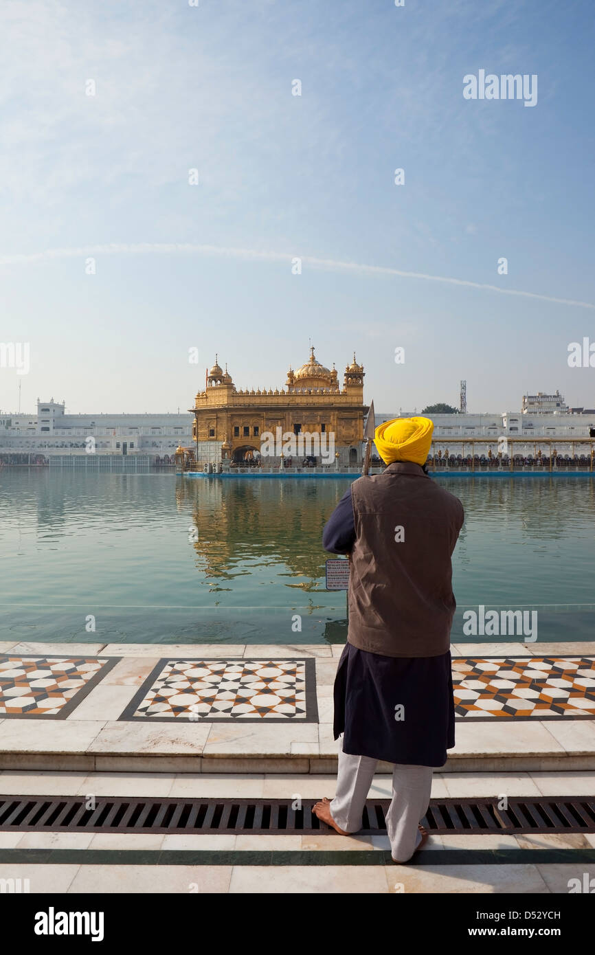 A Temple Guard watching over the magnificent Golden Temple under a blue ...