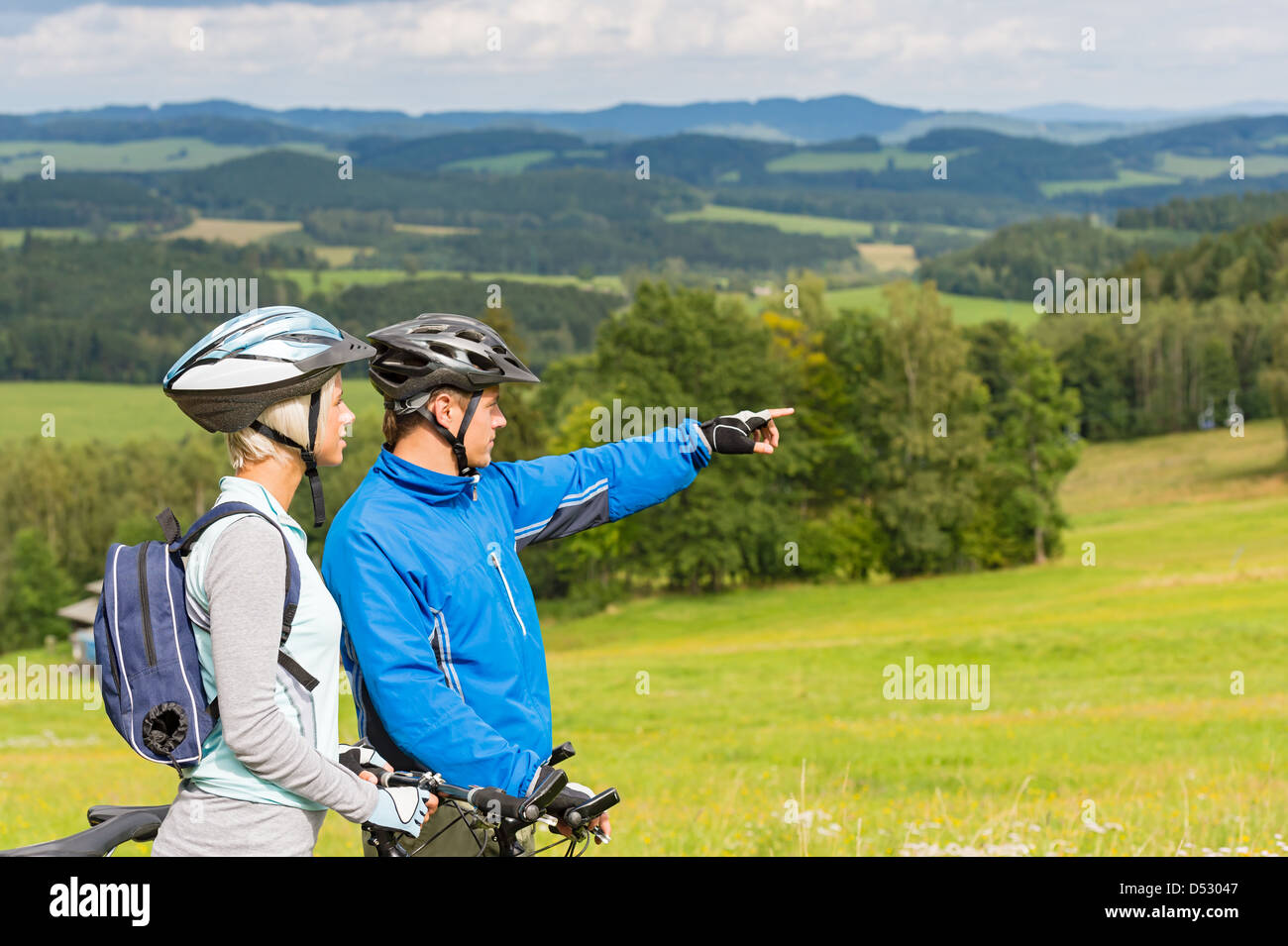 Sporty cyclist couple, man pointing to beautiful landscape Stock Photo ...