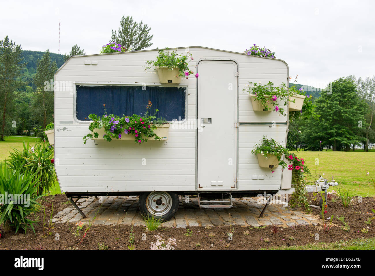 Old caravan with many hanging flowers in pots Stock Photo - Alamy