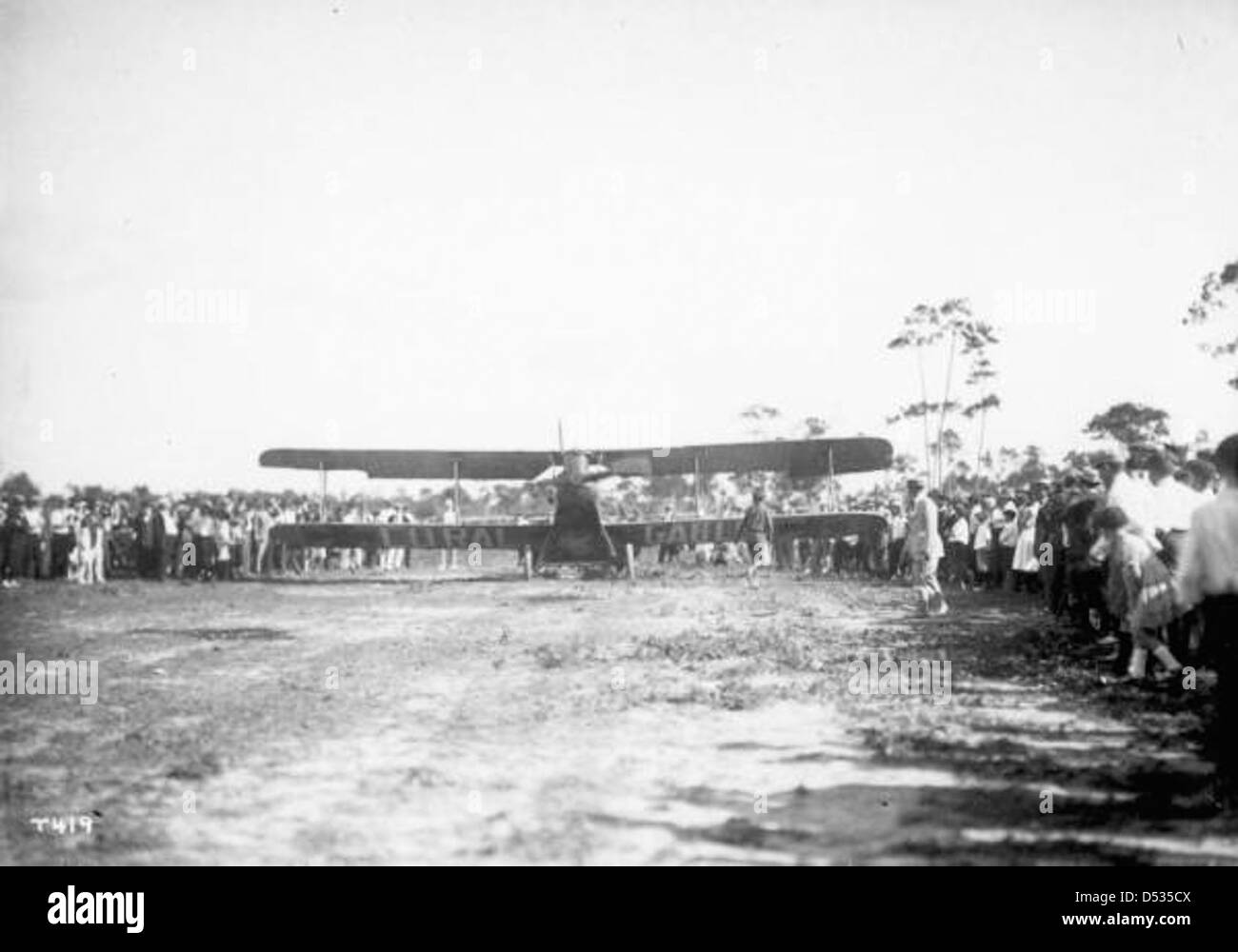 A crowd gathers around a biplane as part of Mabel Cody's Flying Circus ...