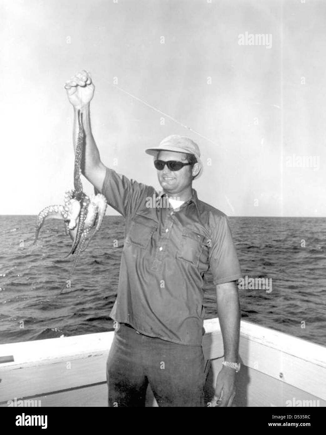 A fisherman holds up a freshly caught squid aboard a boat in Florida ...