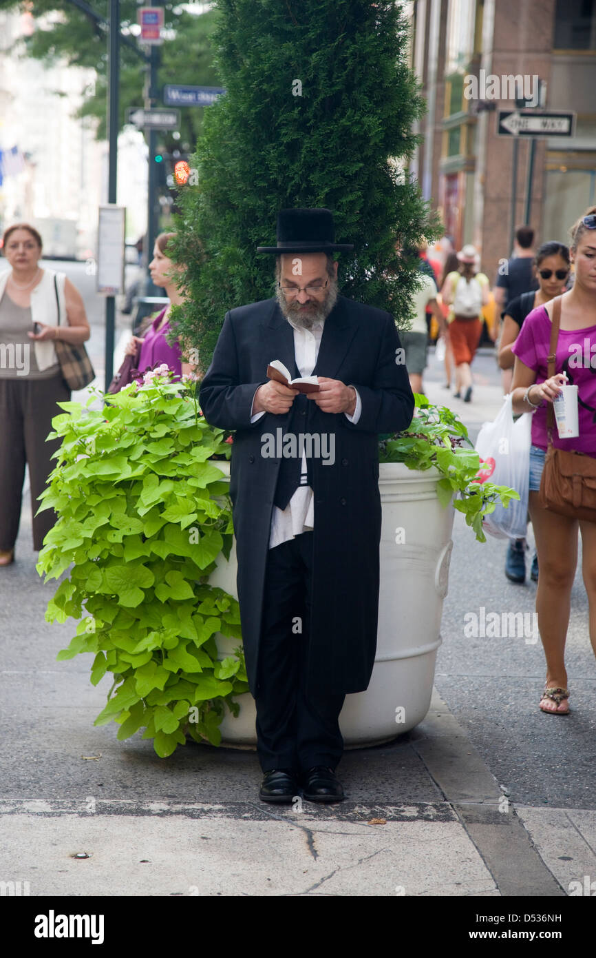 A Jewish gentleman reading a book in the street in New York, USA Stock ...