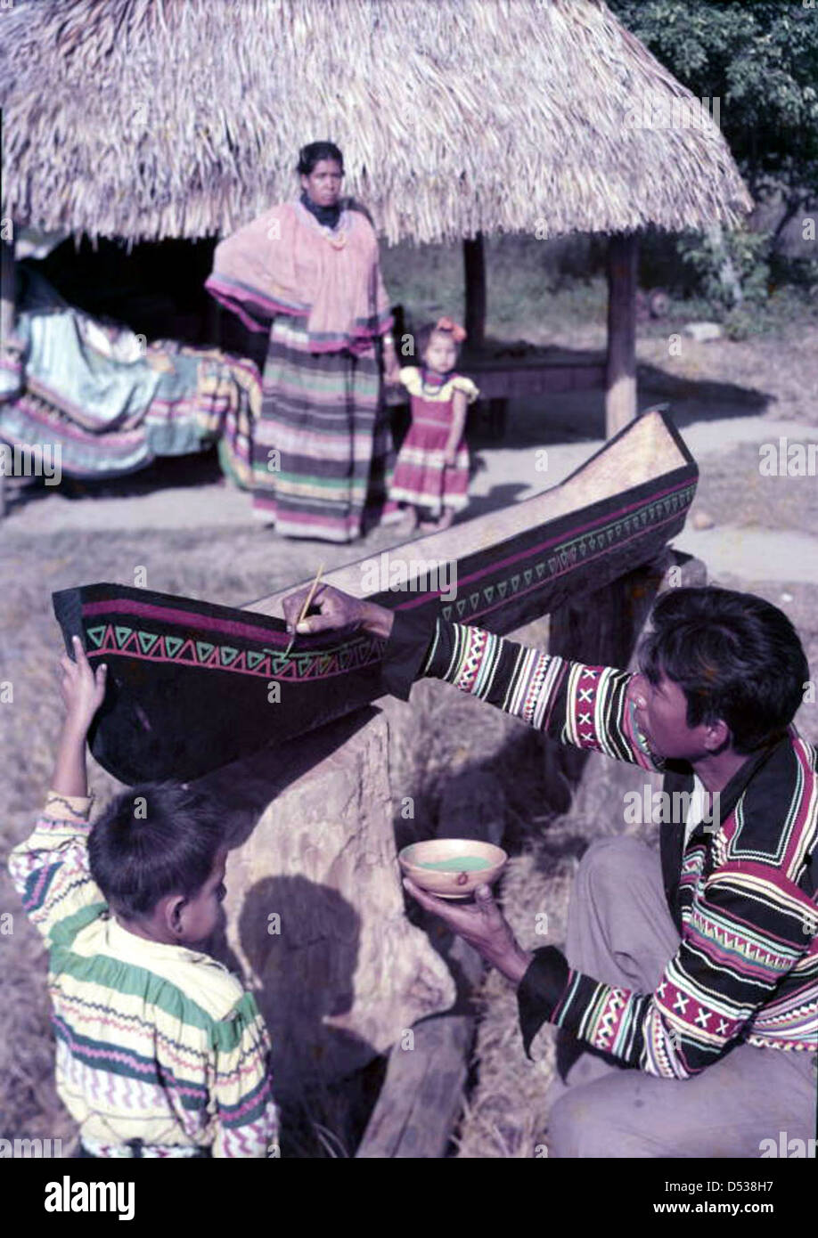 Harry Jumper, a Seminole artist, is seen painting an Indian war canoe ...