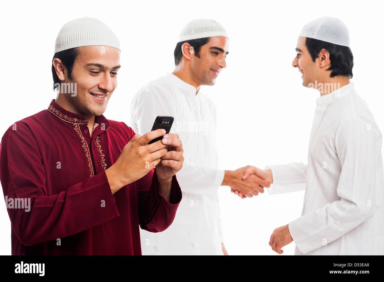 Man text messaging on a mobile phone with his friends shaking hands in ...
