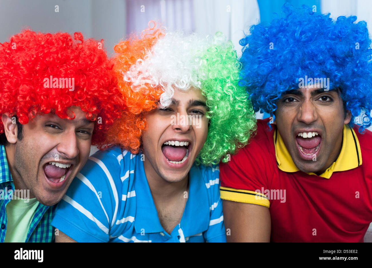 Friends shouting while watching cricket match on the television at home ...