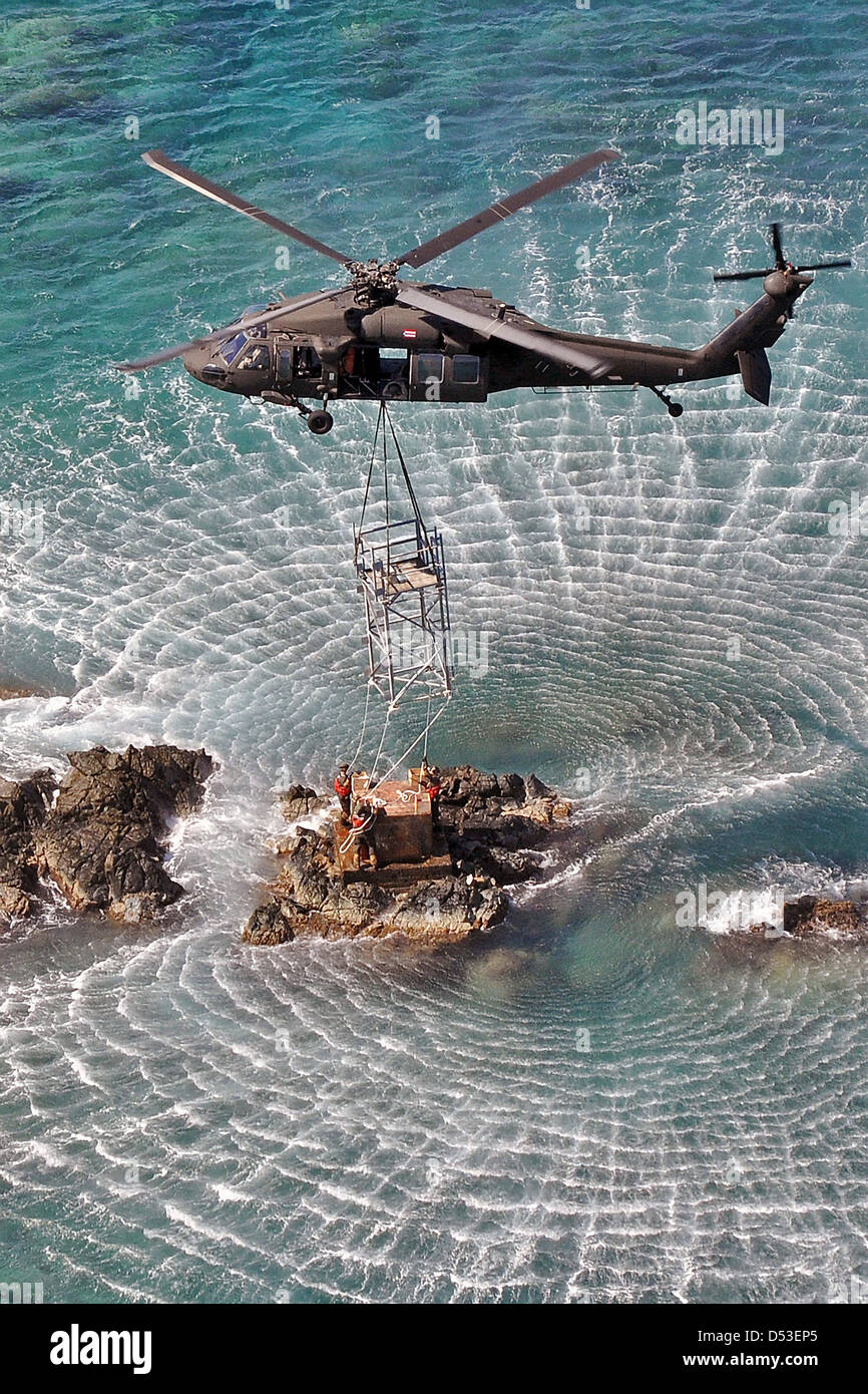 A US Marines UH-60 Black Hawk helicopter uses a sling-load to position ...