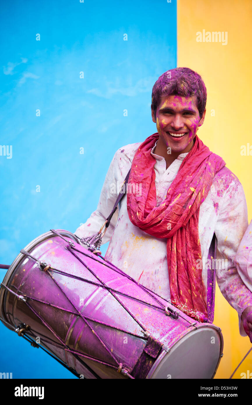Smiling man celebrating Holi with playing dhol Stock Photo - Alamy