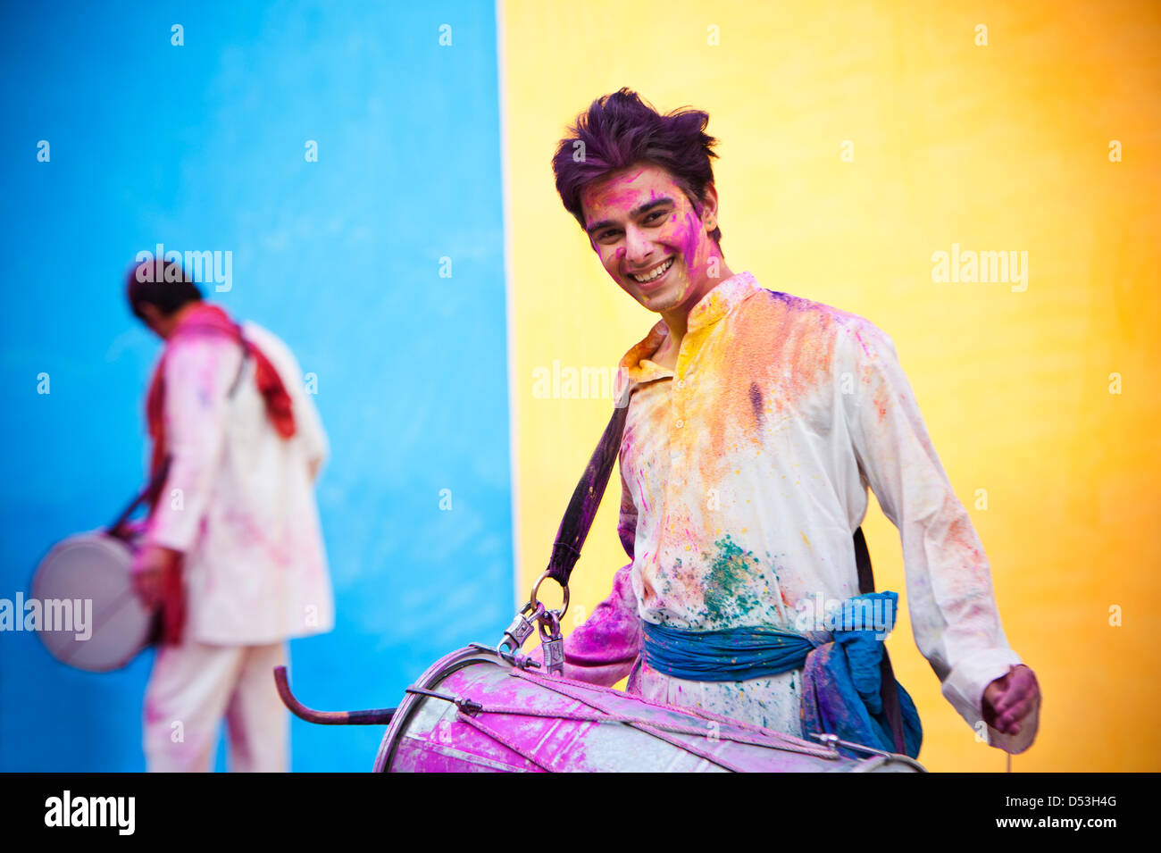 Smiling man celebrating Holi with playing dhol Stock Photo - Alamy