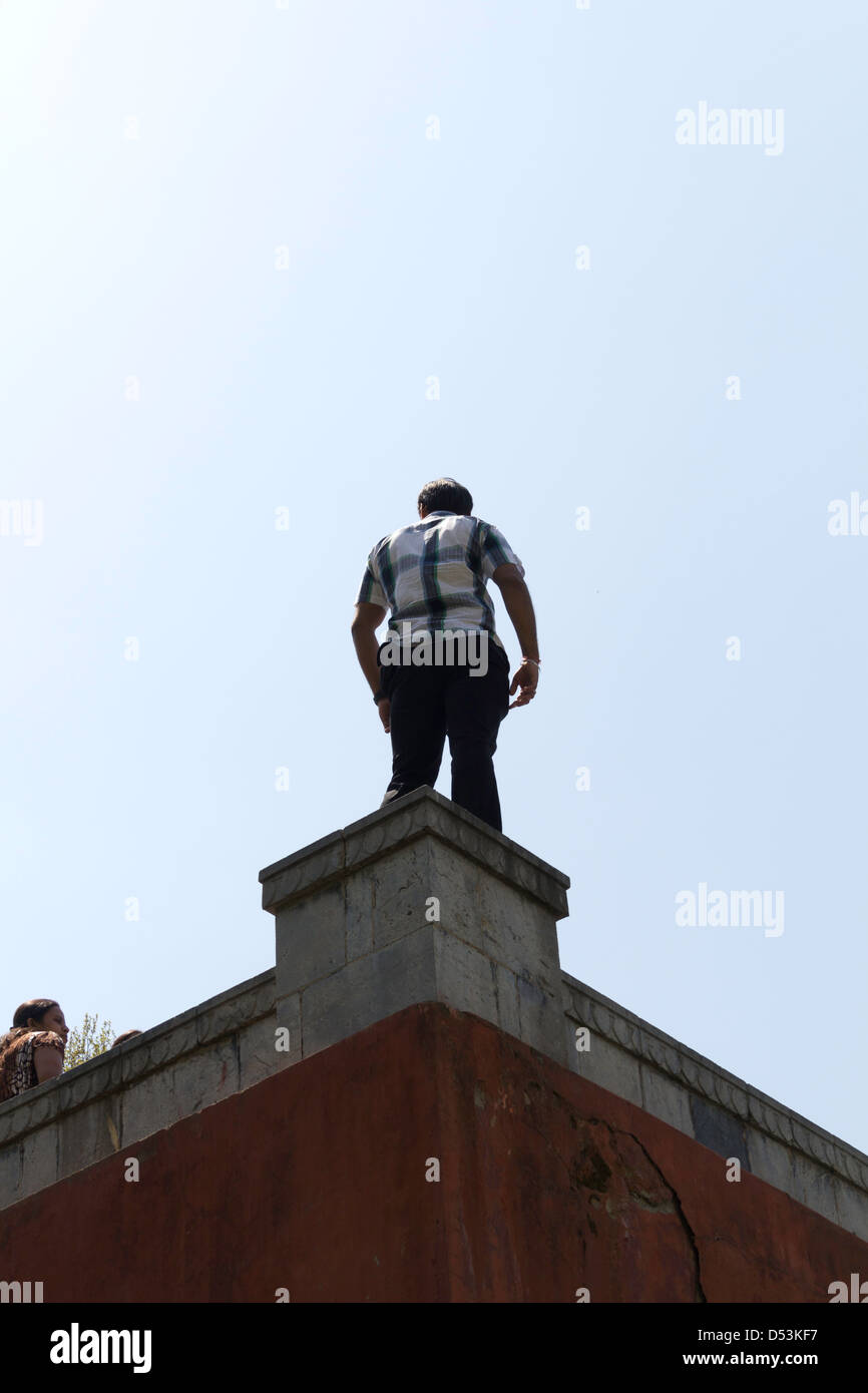 Man standing on the edge of a building, which seems very dangerous, but ...