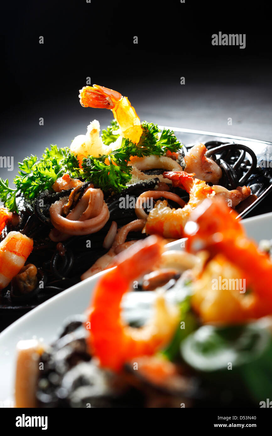 Black spaghetti with seafood on black table Stock Photo - Alamy