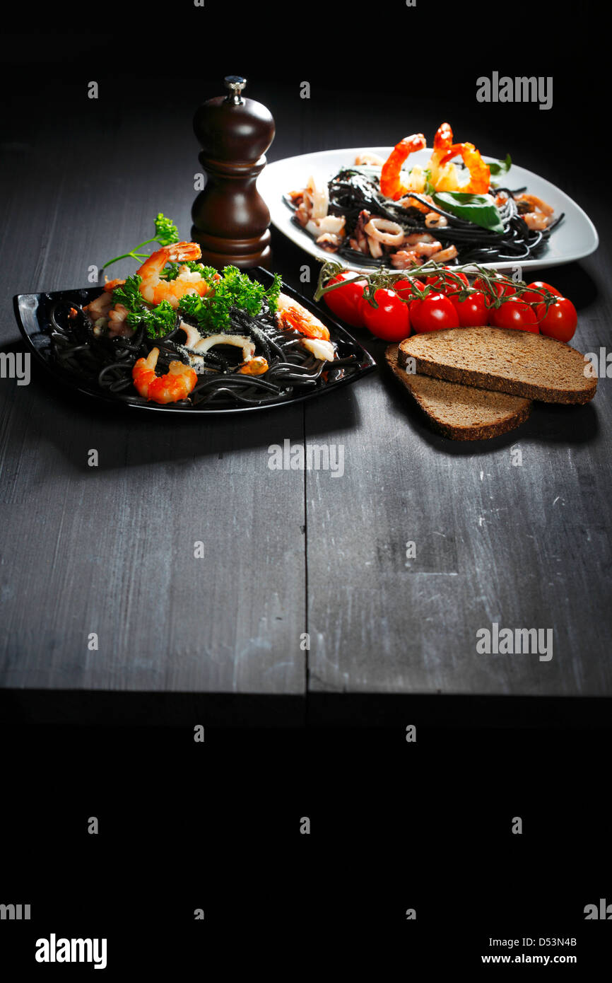 Black spaghetti with seafood on black table Stock Photo - Alamy