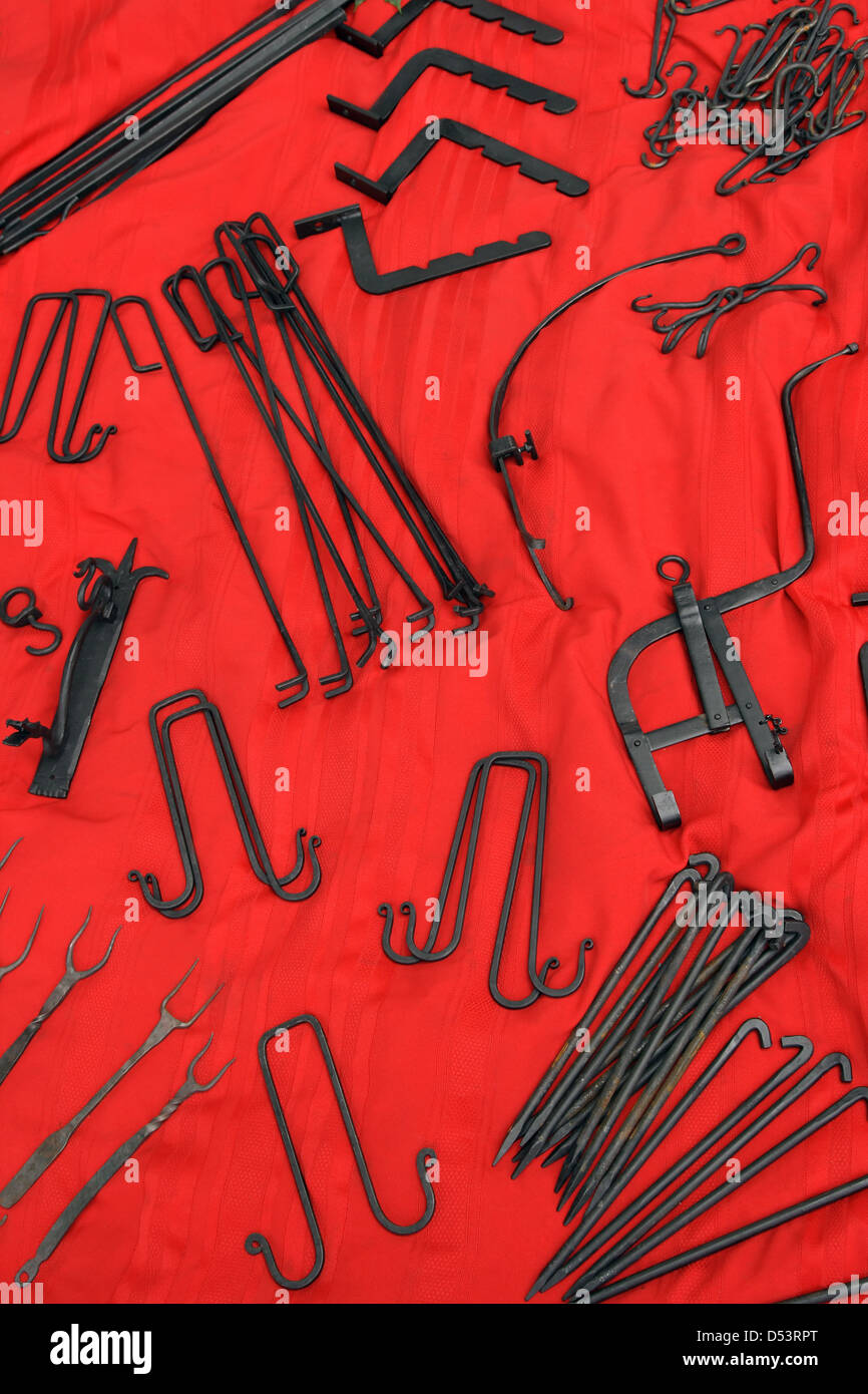 Old-fashioned wrought iron tools on red background Stock Photo - Alamy