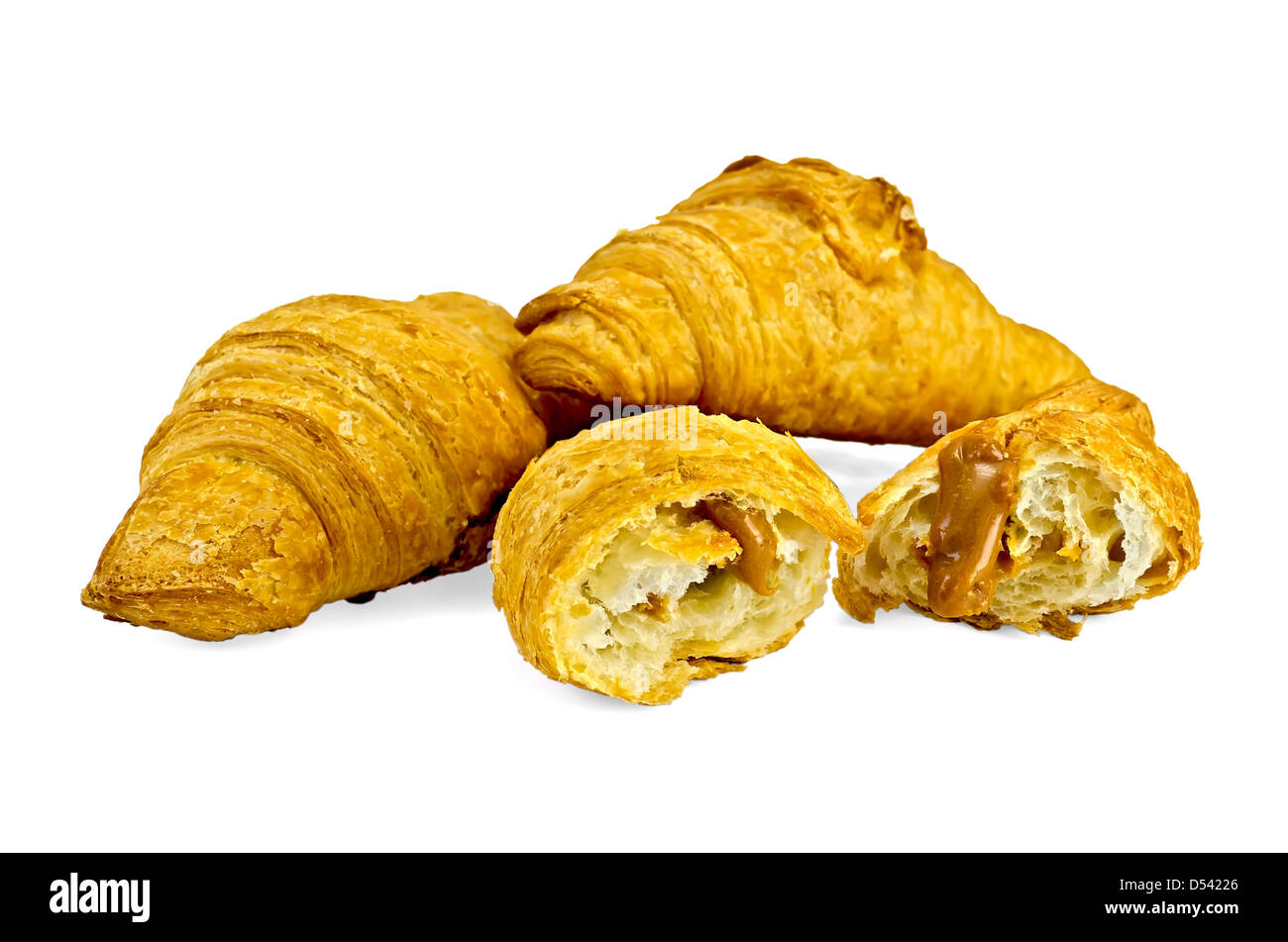 Two whole and one broken croissants filled with condensed milk isolated ...