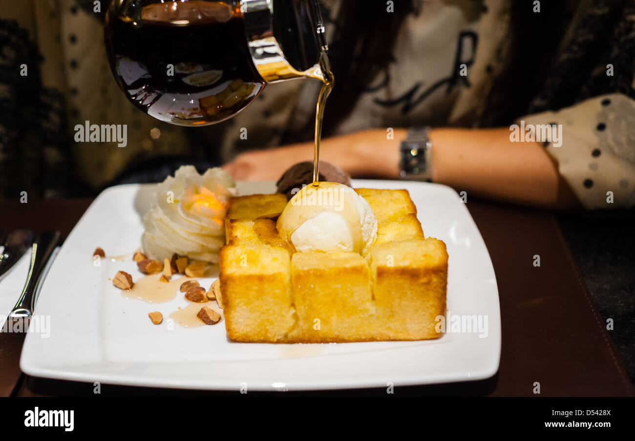 syrup being poured over a scoop of vanilla ice cream on toast Stock ...