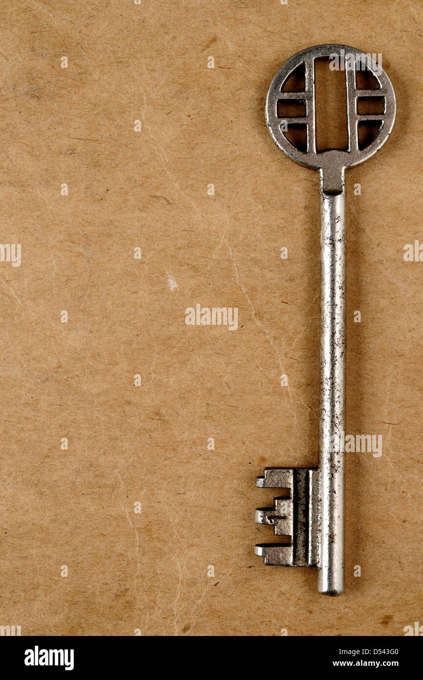 Vintage key on old paper background Stock Photo - Alamy