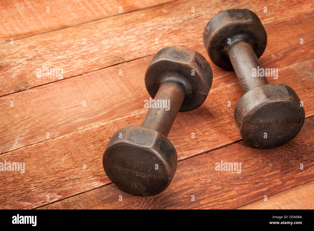 a pair of vintage iron rusty dumbbells on red barn wood background ...