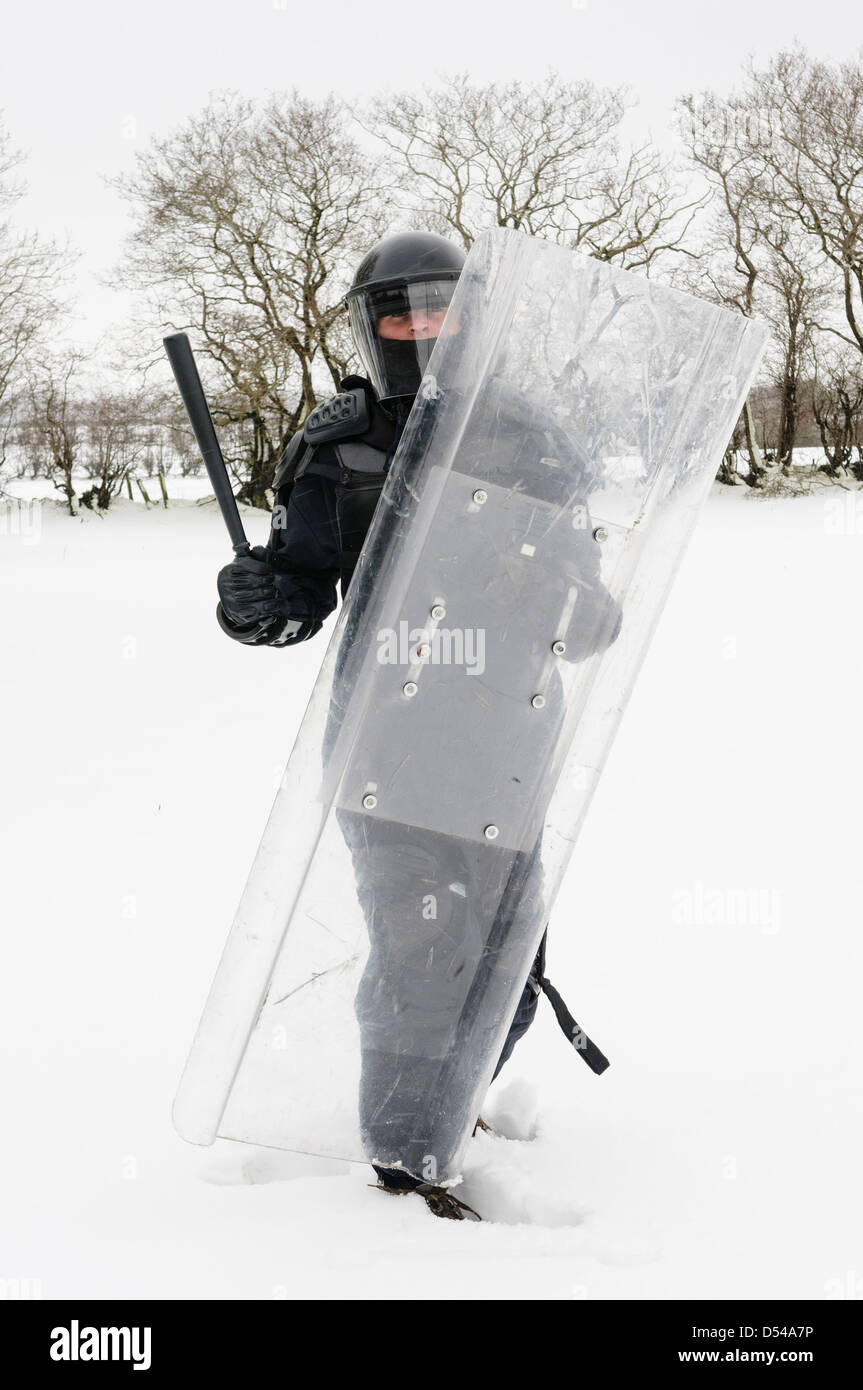 Police officer dressed in riot gear with shield in snow Stock Photo - Alamy