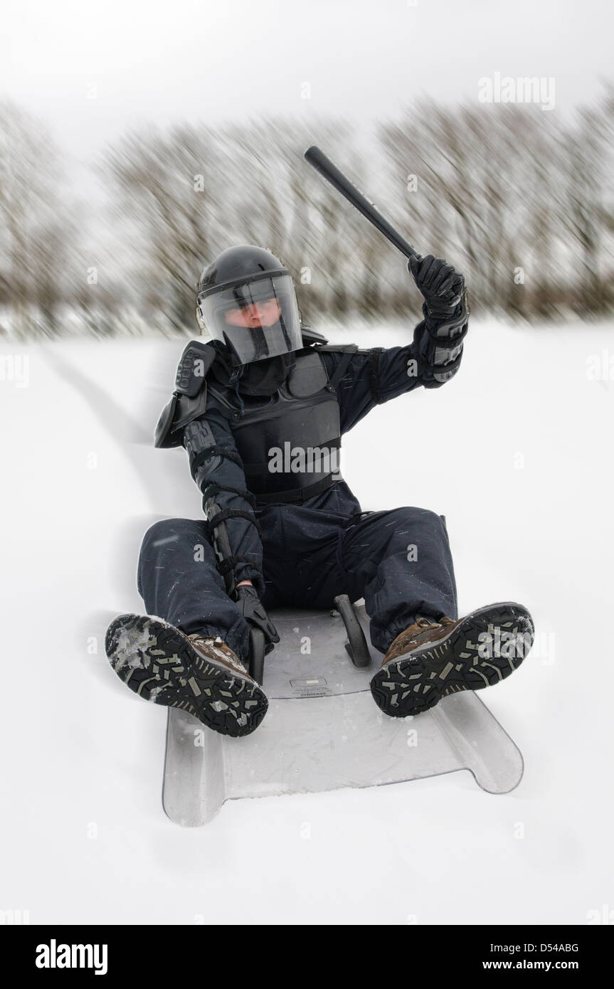 Police officer dressed in riot gear sledging on his shield in snow ...