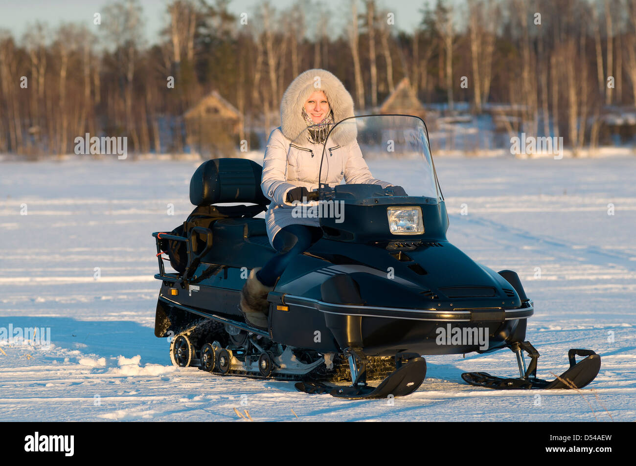 Girl on a snowmobile in the sunset rays Stock Photo - Alamy