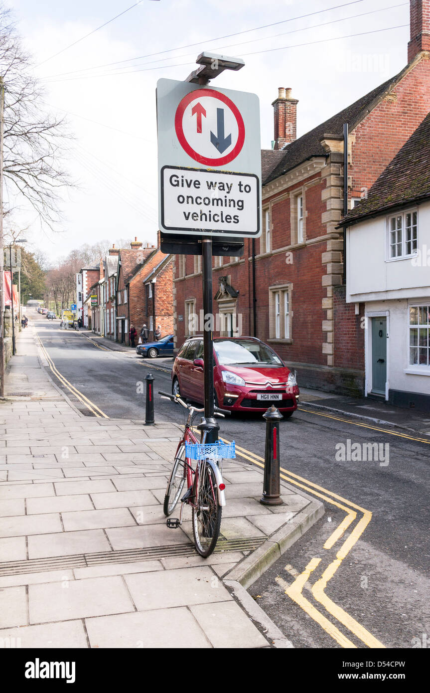 Bicycle leaning against UK give way traffic sign with car driving past ...