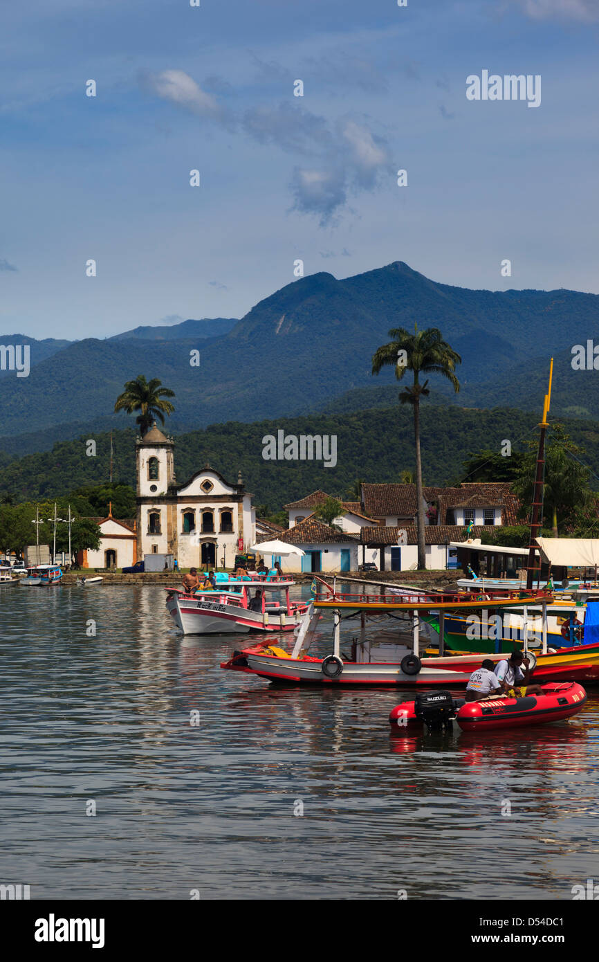 Harbour with colourful excursion boats, Capela de Santa Rita church at ...