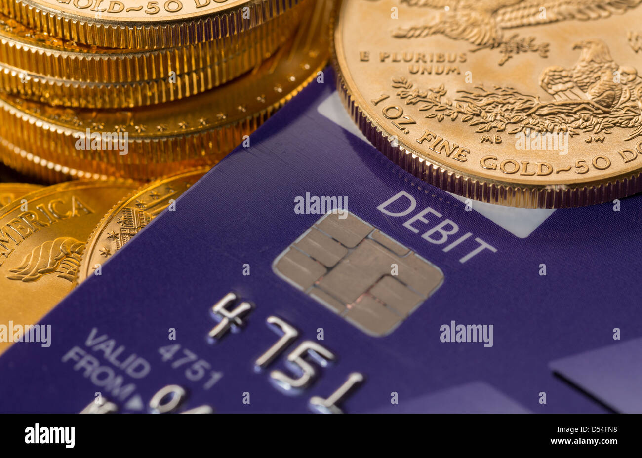Solid gold coins contrasted with debit word on plastic credit card ...