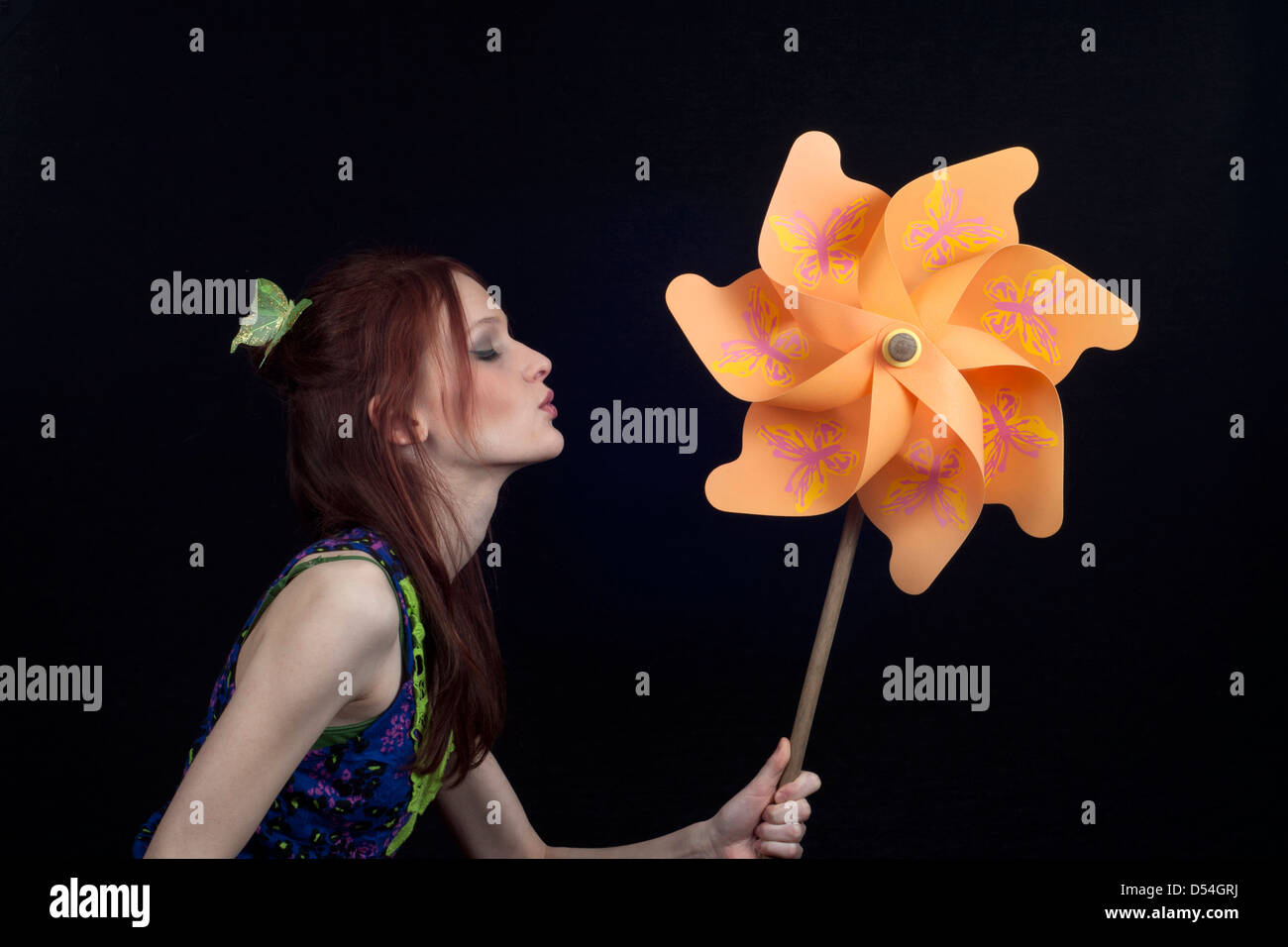 Girl with an orange pinwheel against black background Stock Photo - Alamy