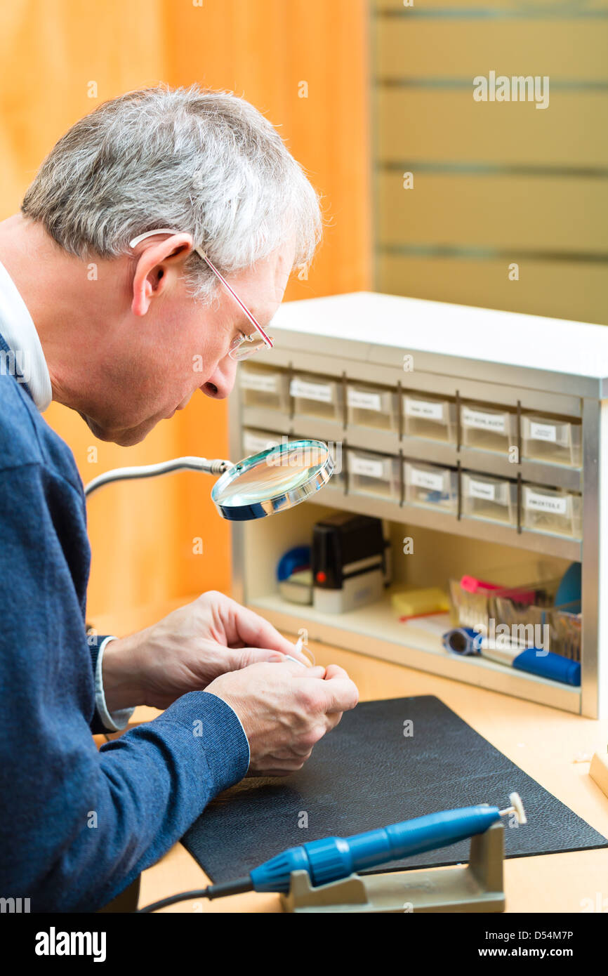 hearing aid acoustician at work, he is working on a hearing aid for ...