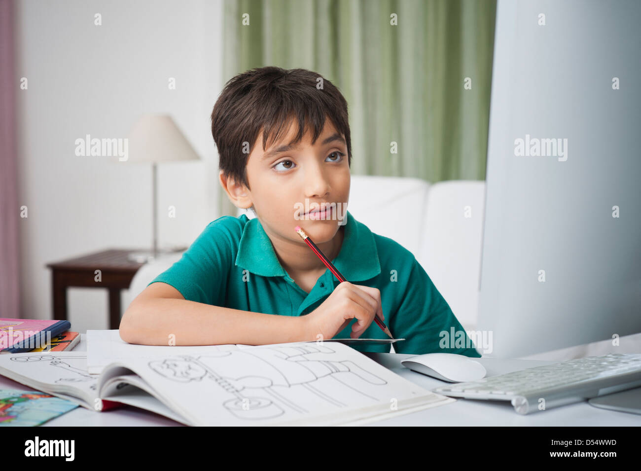 Boy looking at desktop pc while doing his homework Stock Photo - Alamy