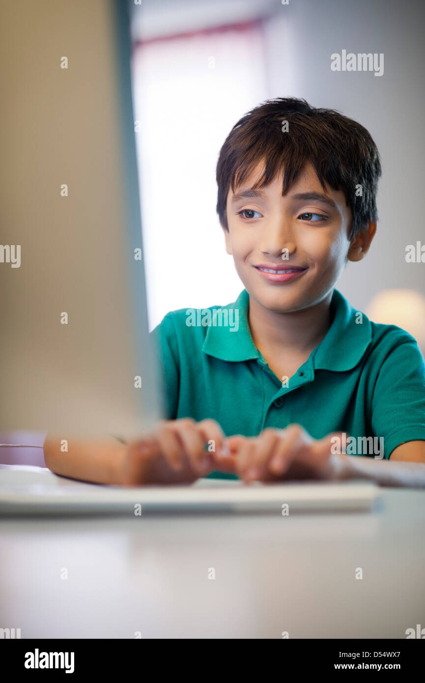 Boy using a desktop pc and smiling at home Stock Photo - Alamy