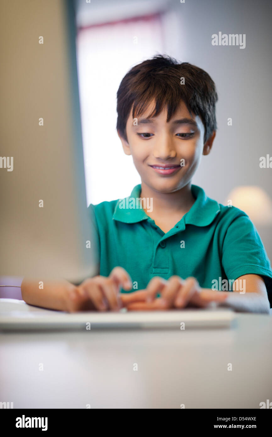 Boy using a desktop pc and smiling at home Stock Photo - Alamy