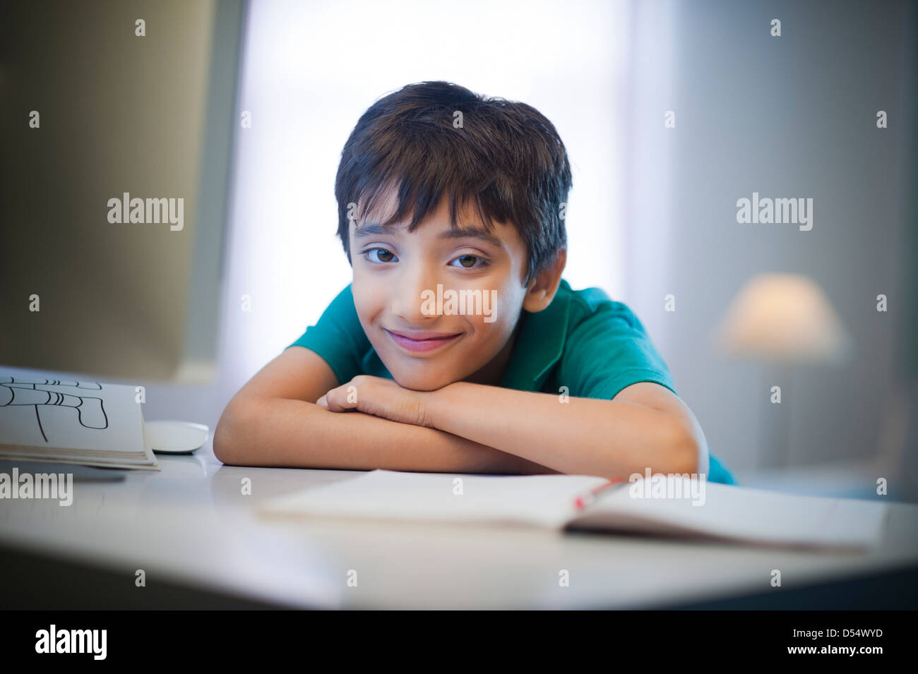 Portrait of a boy smiling at a study table Stock Photo - Alamy