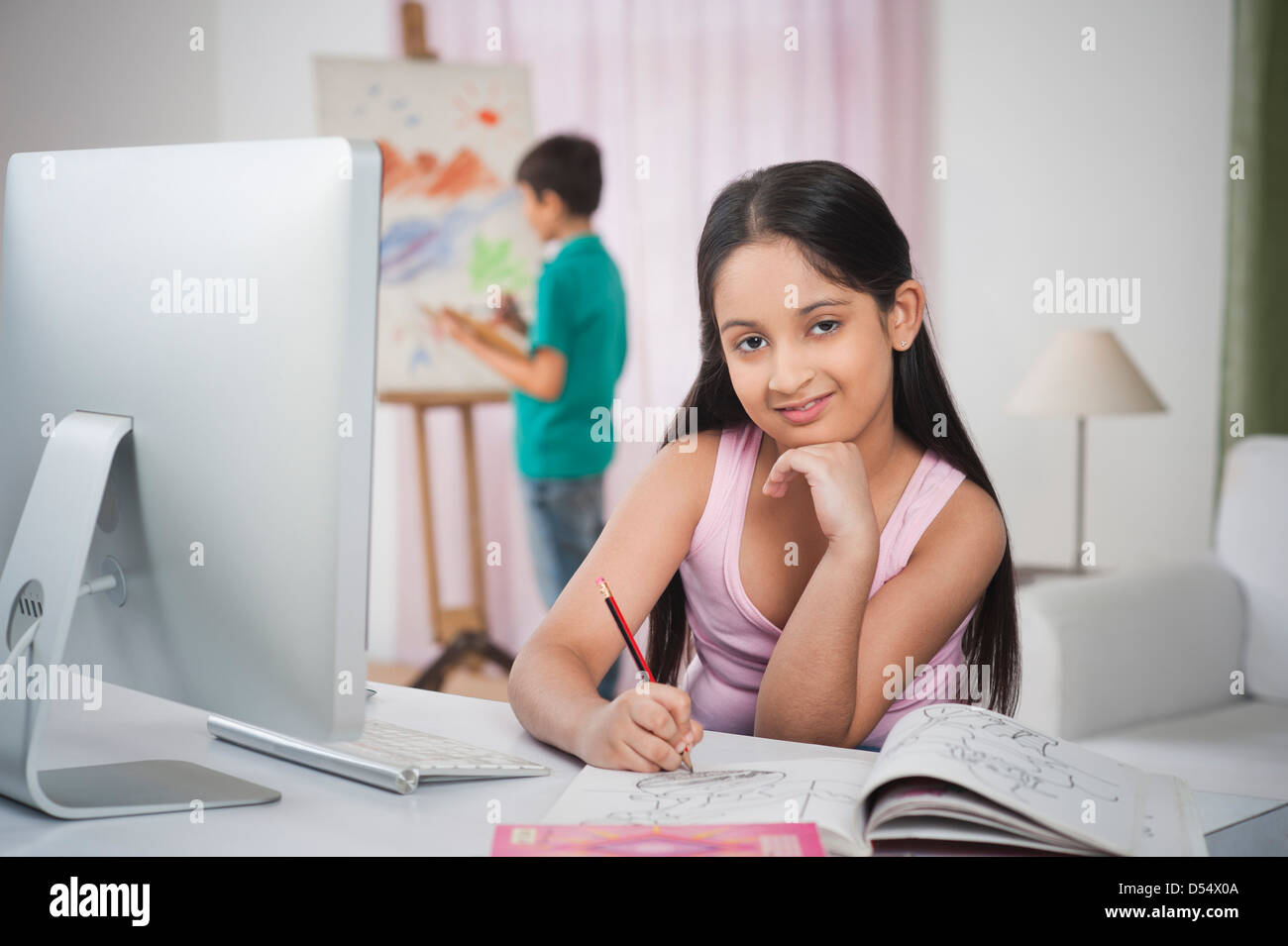 Girl studying at a study table with her brother painting on artists ...