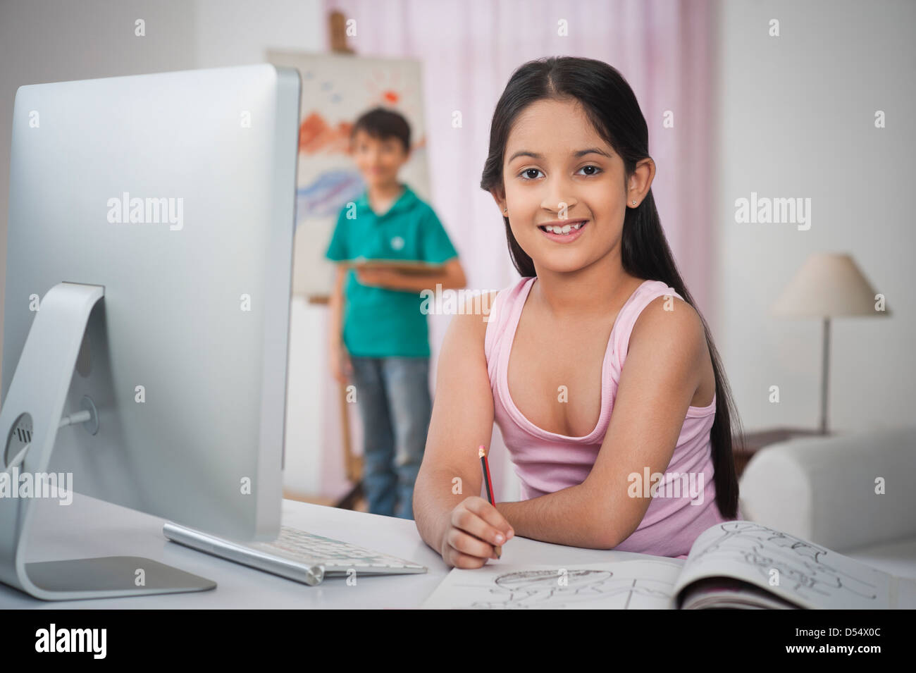 Girl studying at a study table with her brother painting on artists ...
