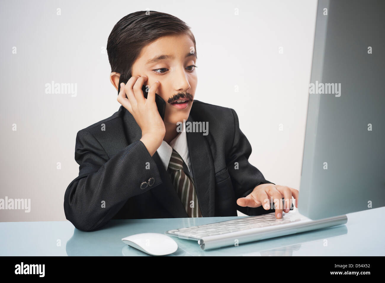 Boy imitating like businessman talking on a mobile phone while working ...