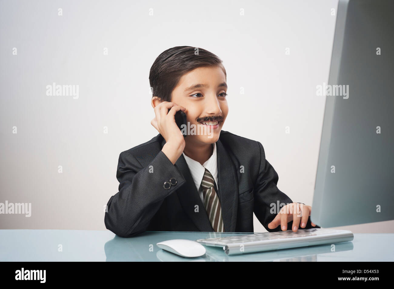 Boy imitating like businessman talking on a mobile phone while working ...