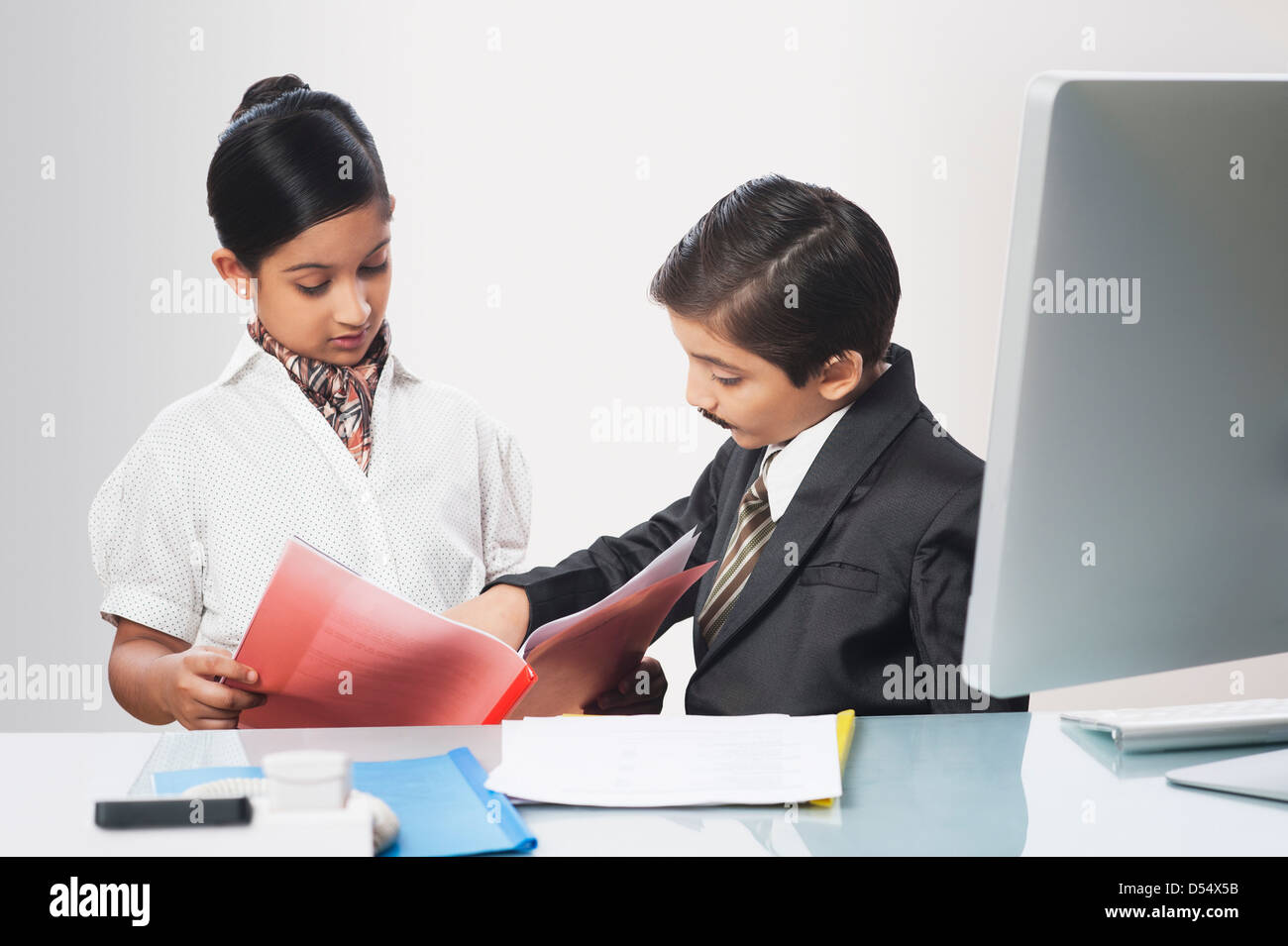 Boy imitating like businessman examining documents with a girl ...