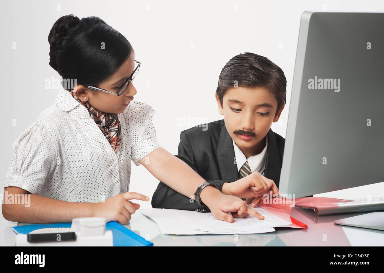 Boy imitating like businessman examining documents with a girl ...