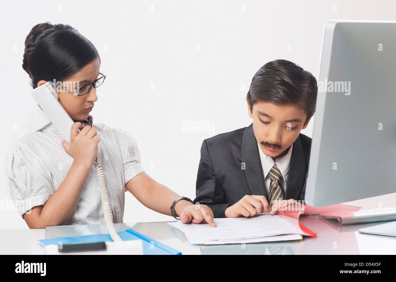 Boy imitating like businessman examining documents with a girl ...