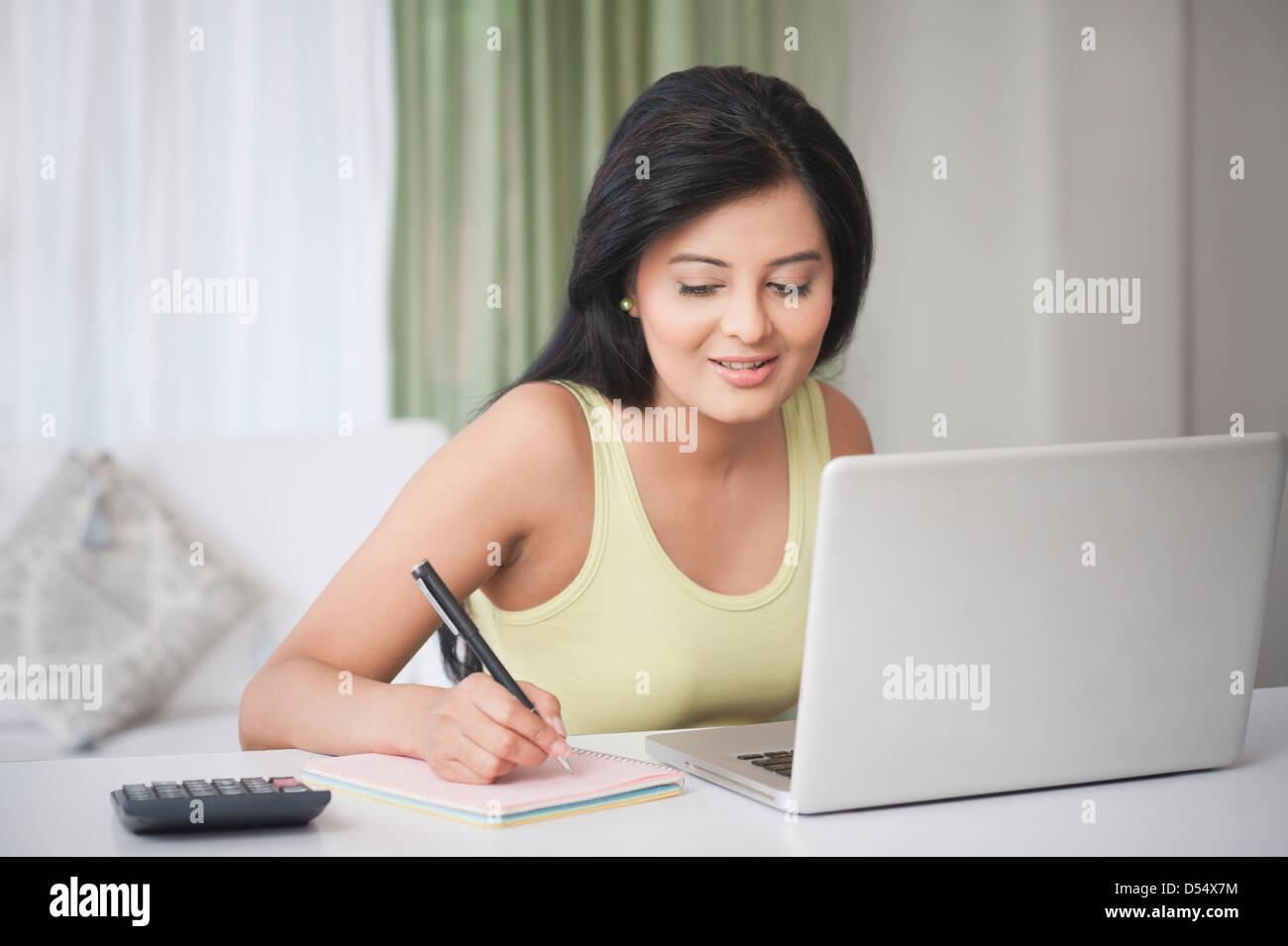 Woman sitting in front of a laptop and writing in a diary Stock Photo ...