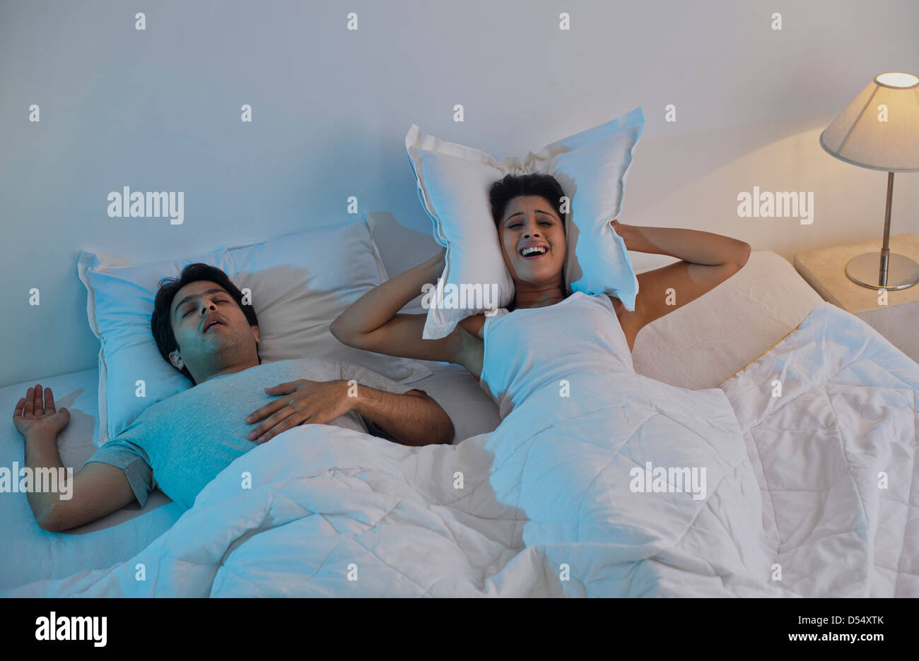 Man snoring with his wife covering ears with pillow on the bed Stock ...