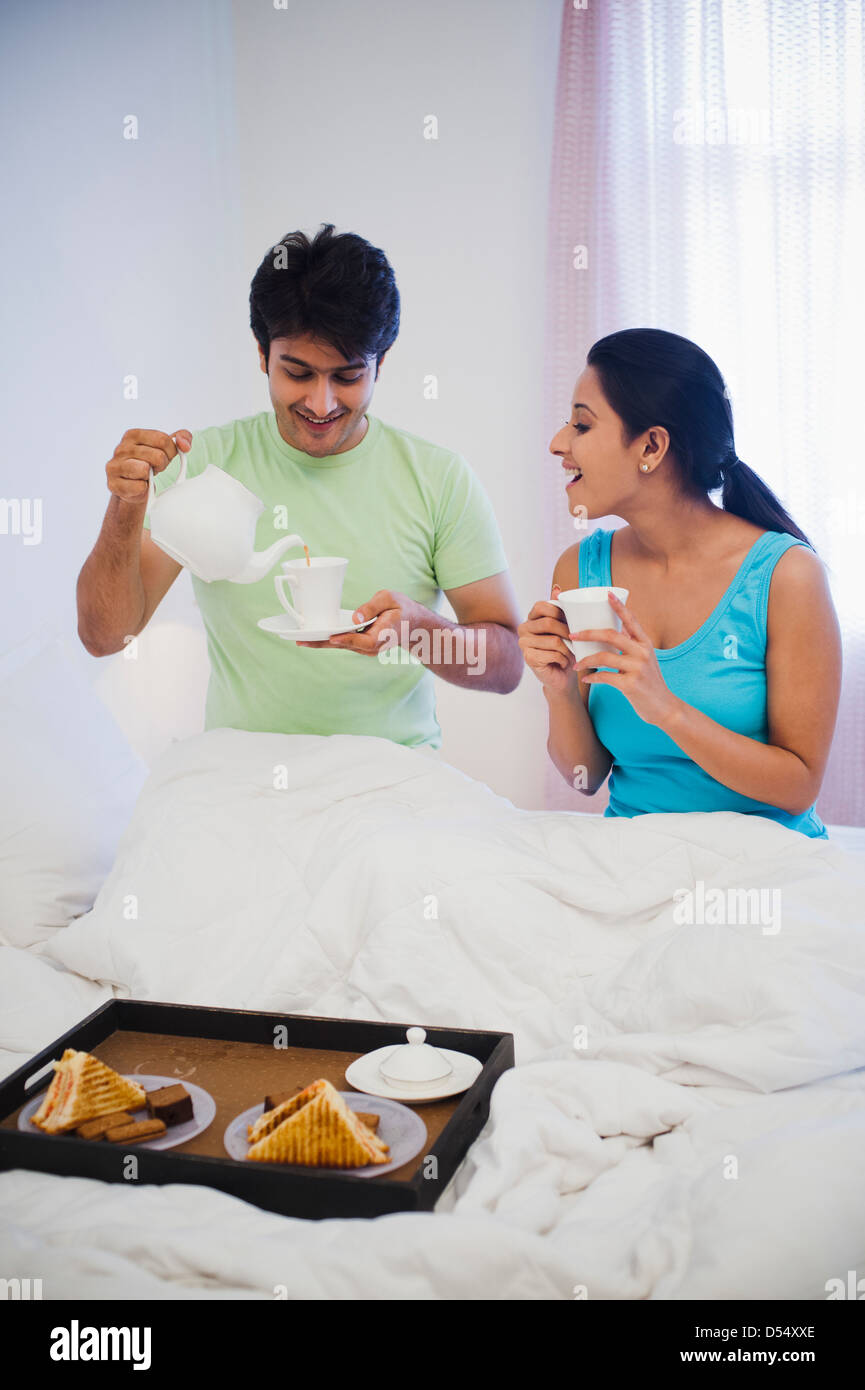 Couple enjoying tea with breakfast on the bed Stock Photo - Alamy