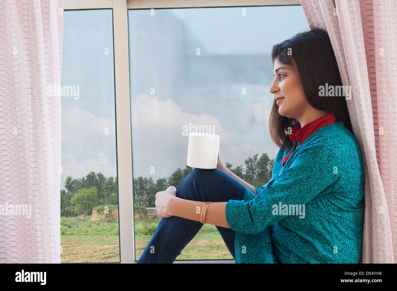 Woman sitting at a window and drinking coffee Stock Photo - Alamy