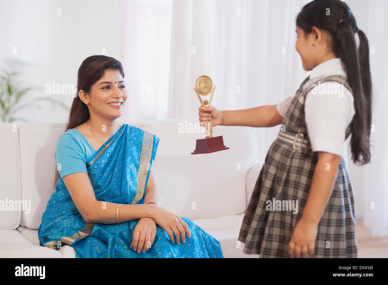 Girl showing her winning trophy to her mother Stock Photo - Alamy