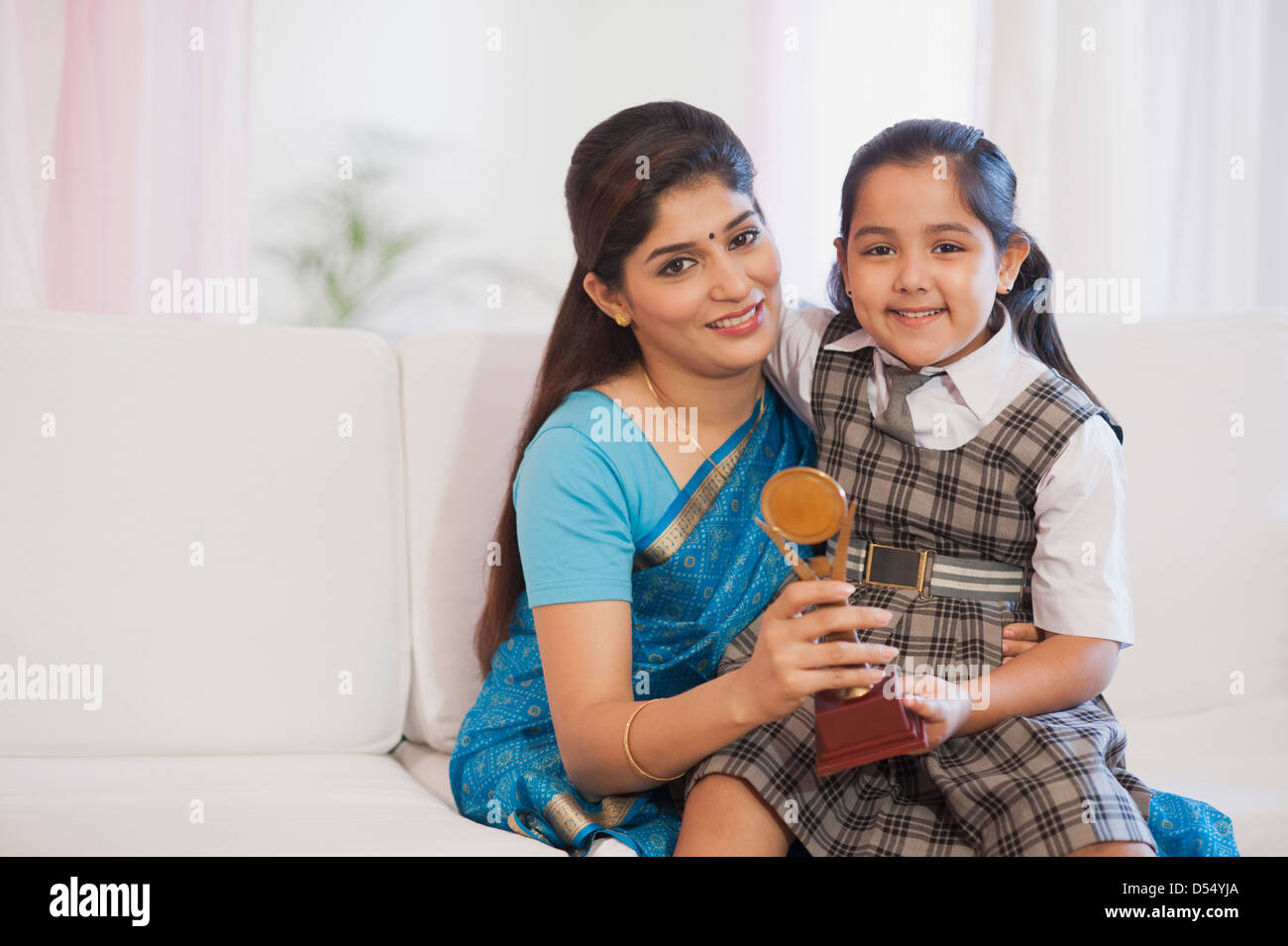 Portrait of a woman and her daughter holding a trophy Stock Photo - Alamy