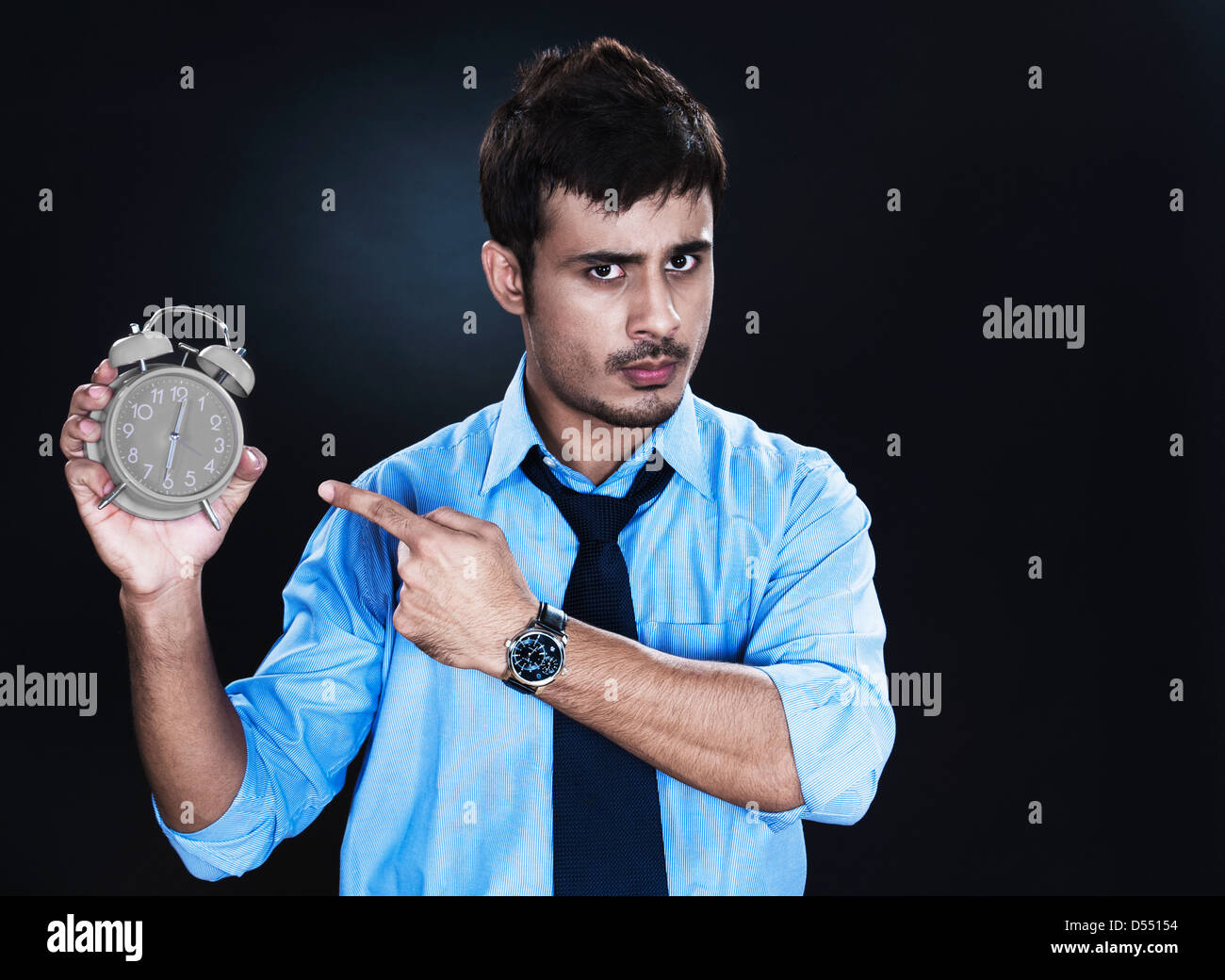 Angry businessman pointing towards an alarm clock Stock Photo - Alamy