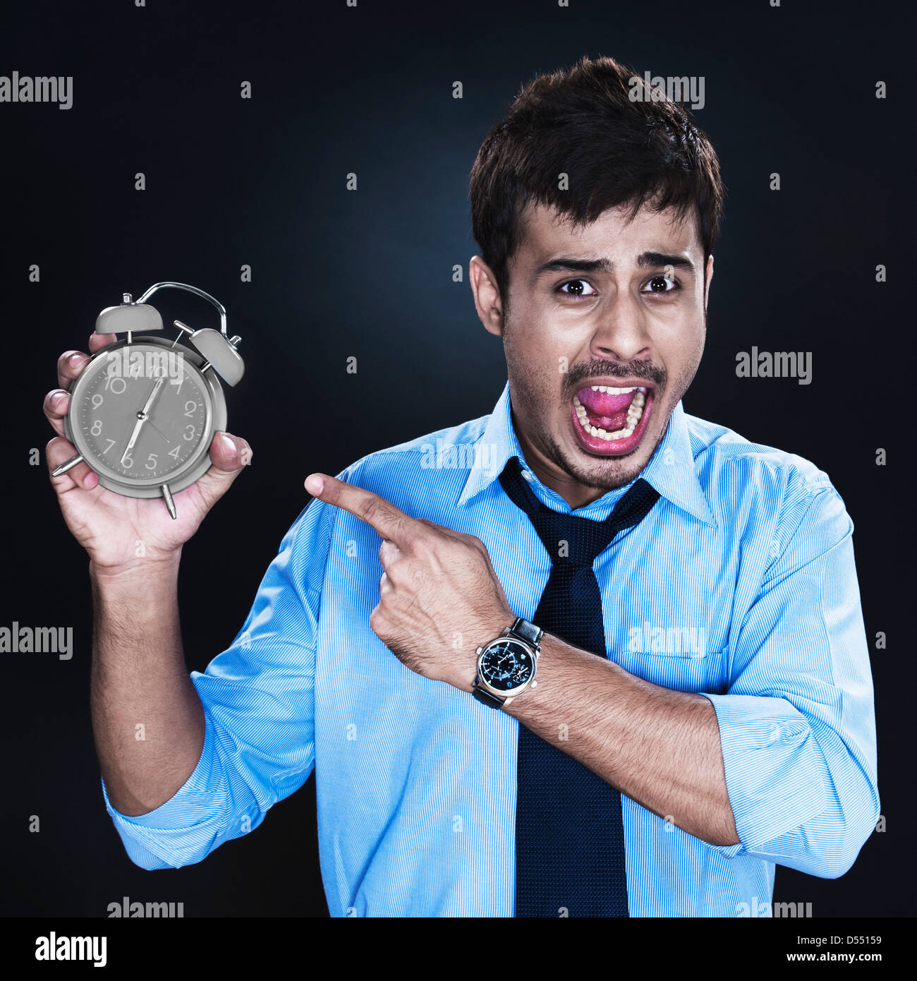 Angry businessman pointing towards an alarm clock Stock Photo - Alamy