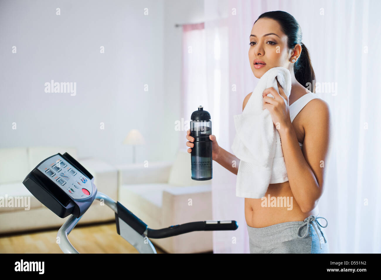 Woman standing on a treadmill and wiping her sweat Stock Photo - Alamy