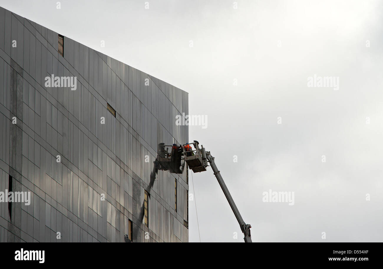 window cleaners on cherry picker crane washing tall glass sided ...